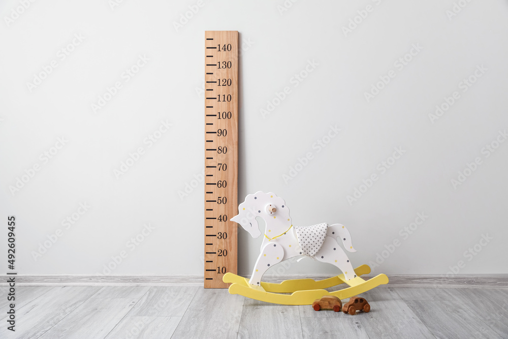 Big ruler for height measuring, rocking horse and wooden toy cars near ...