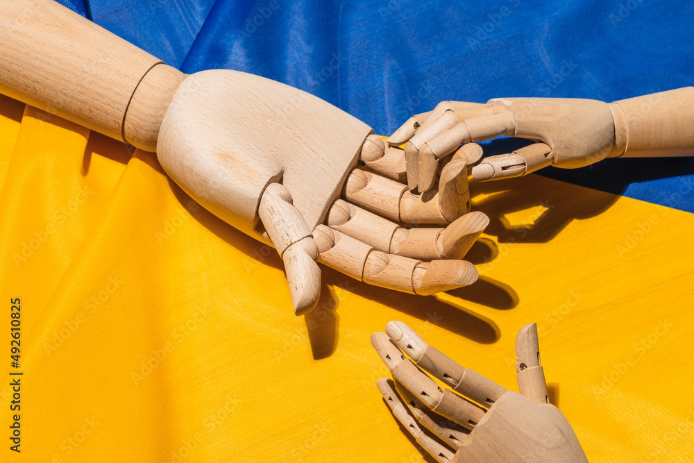 Holding wooden hands on Ukrainian flag Stock Photo | Adobe Stock