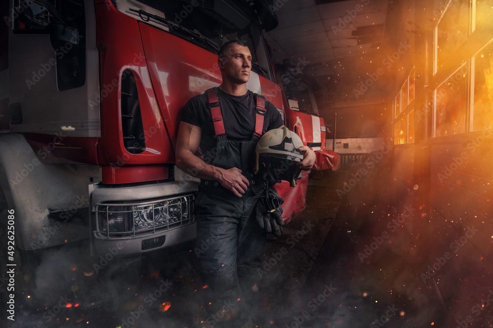 Poster Handsome firefighter with hard hat indoors fire station – Wall ...