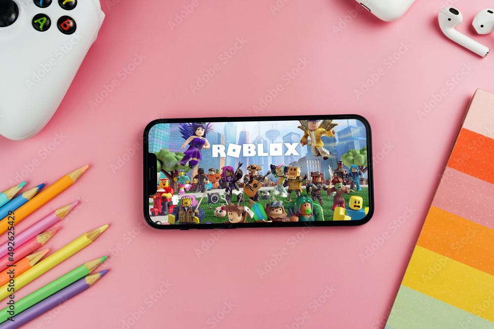 Roblox mobile game app on the smartphone screen. Pink background with ...