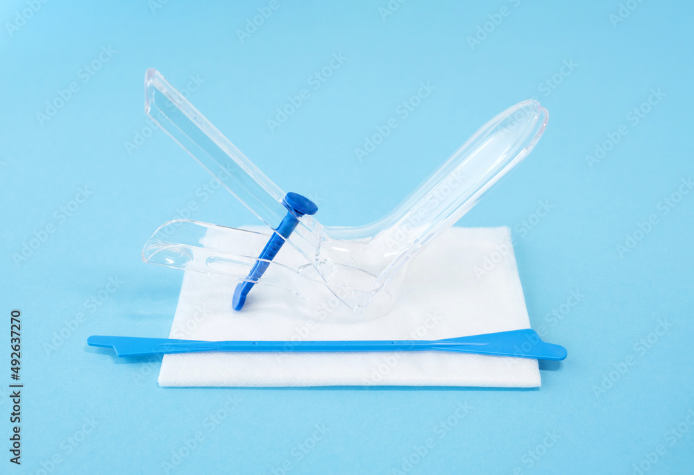 Basic set for vaginal examination on blue background. Gynecological speculum, spatula, napkin ...