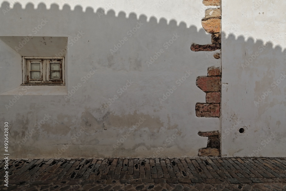 Small recessed window-peeling paint casing-roof shadow cast-whitewashed ...