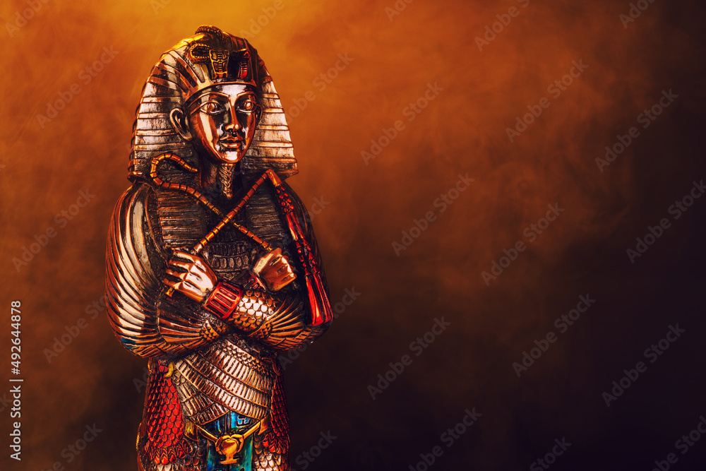 Egyptian pharaoh figurine in yellow smoke on a black background. side ...