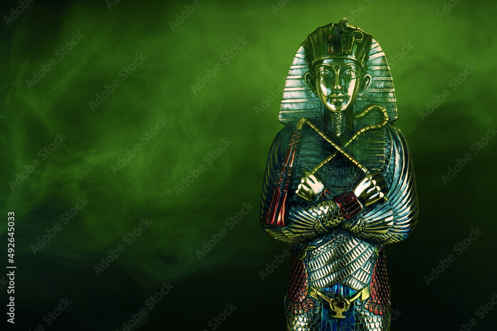 Egyptian pharaoh figurine in green smoke on a black background. side ...