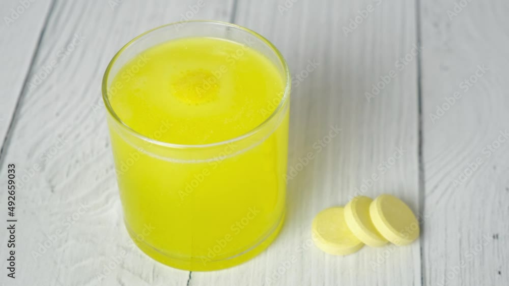 Yellow effervescent tablet dissolves in glass of water. Medicines on ...