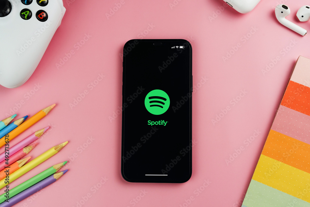 Spotify Music app on the smartphone screen. Pink background with school supplies, accessories ...
