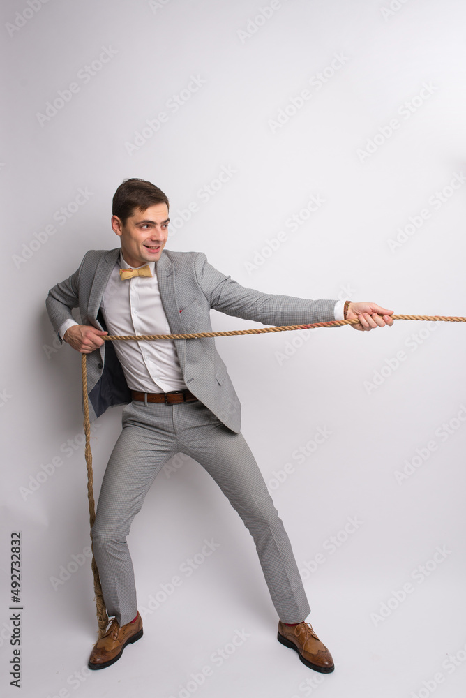 Strong man pulling rope. Photo of sporty man on grey background ...