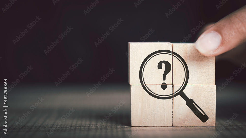 Hand hold magnifying glass and question mark sign icon in wooden cube ...
