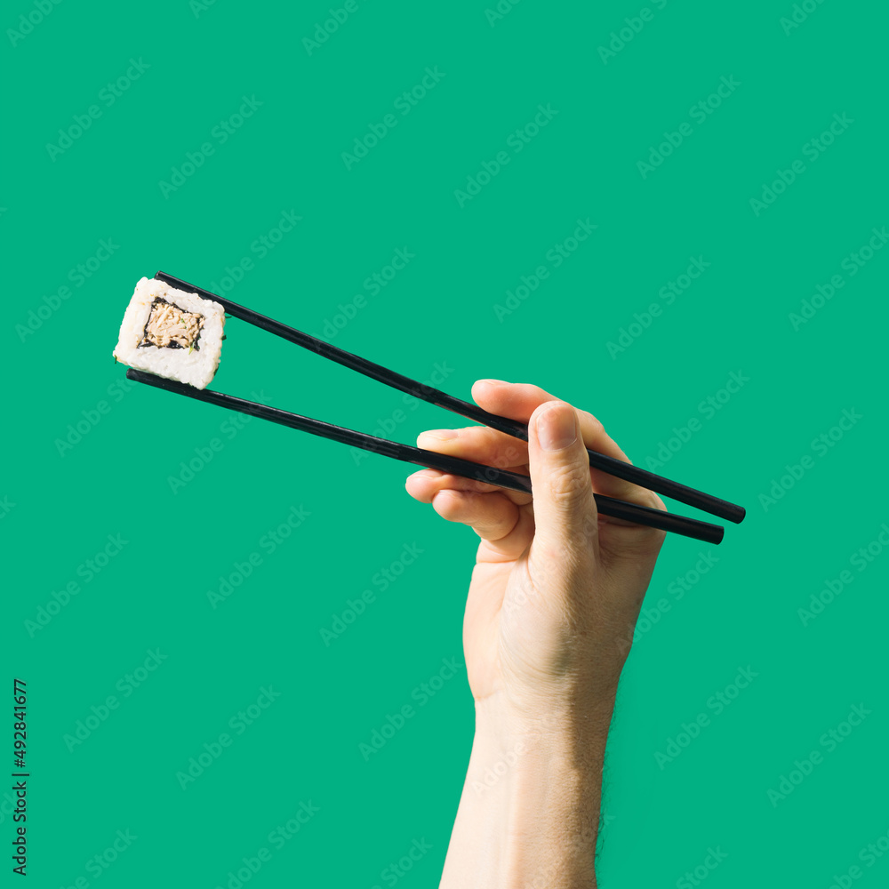 Flat lay minimal sushi concept. Man hand holding black chopstick with ...