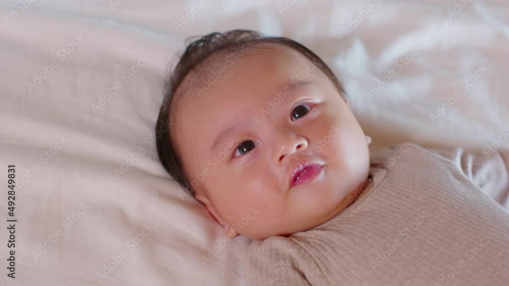 Top view happy newborn baby lying on a white bed and blanket comfortable and safety.Cute Asian ...