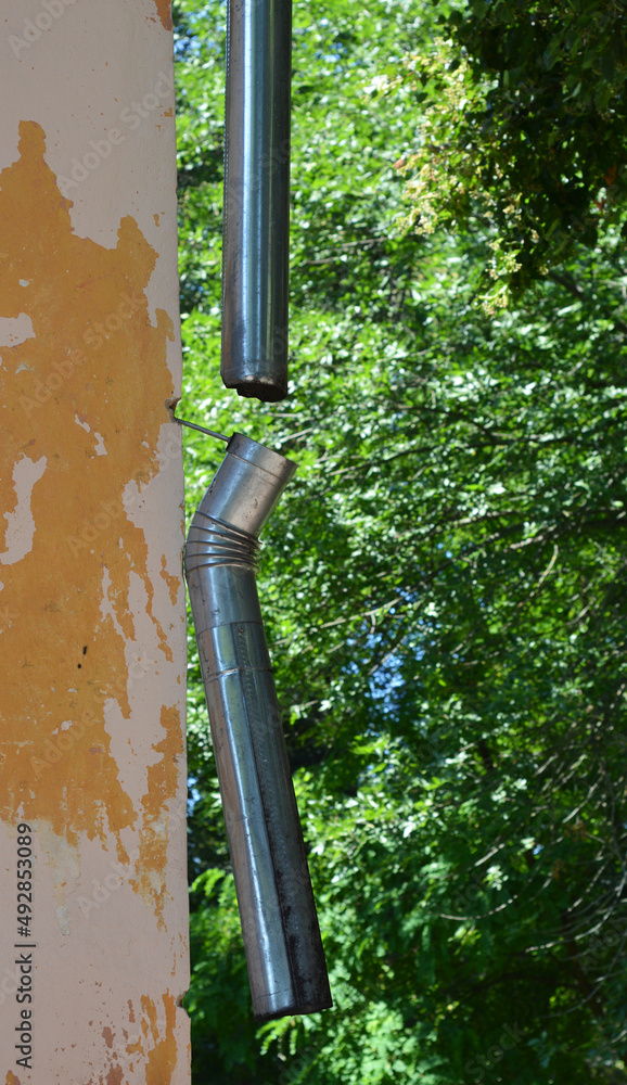 Repairing, fixing a broken metal downspout, downpipe of an old house. A ...