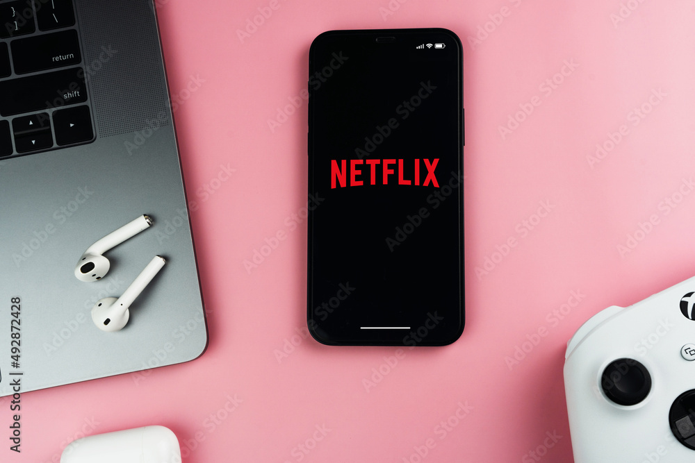 Netflix app on the smartphone screen. Pink background with computer ...