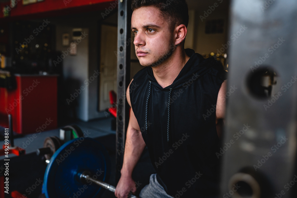 one man side view of adult male amateur bodybuilder standing at the gym ...