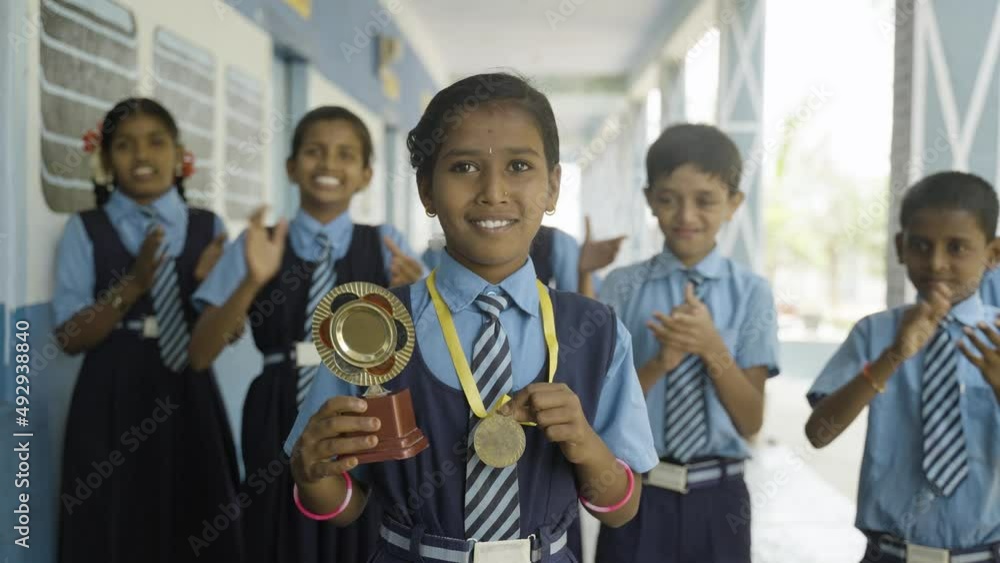 Proud girl with winner trophy and medal with cheeful students ...