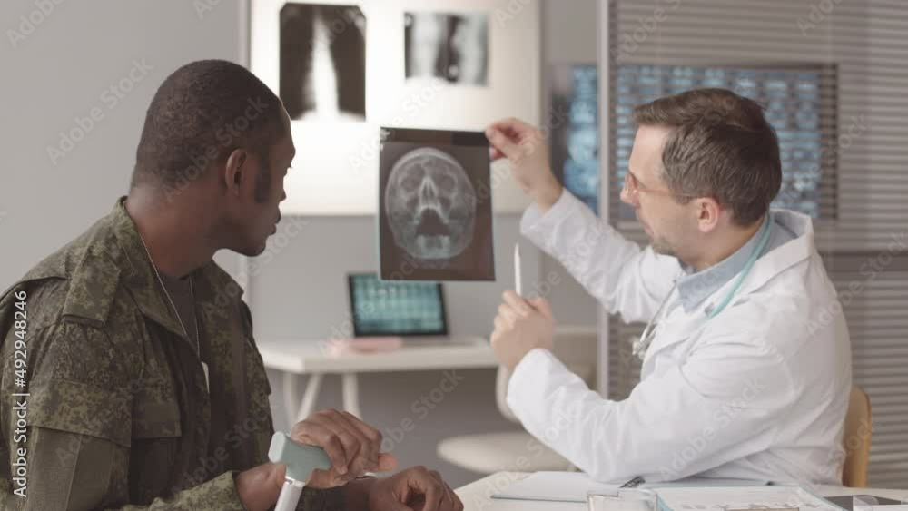Waist up slowmo of Caucasian male doctor showing Black army officer in ...