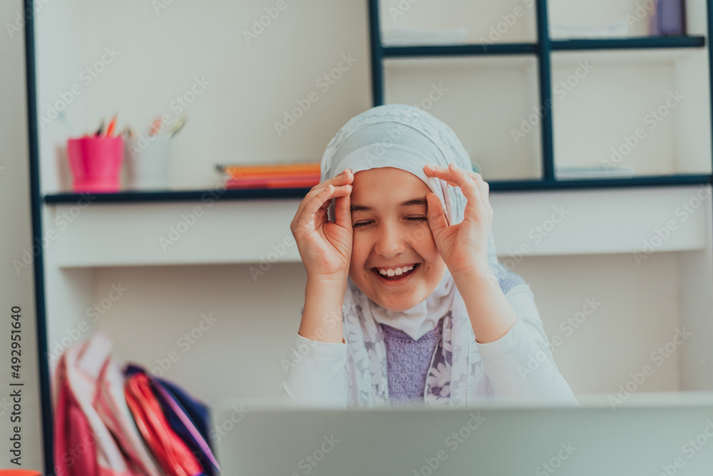 Muslim girl in hijab laughing while having online communication with ...