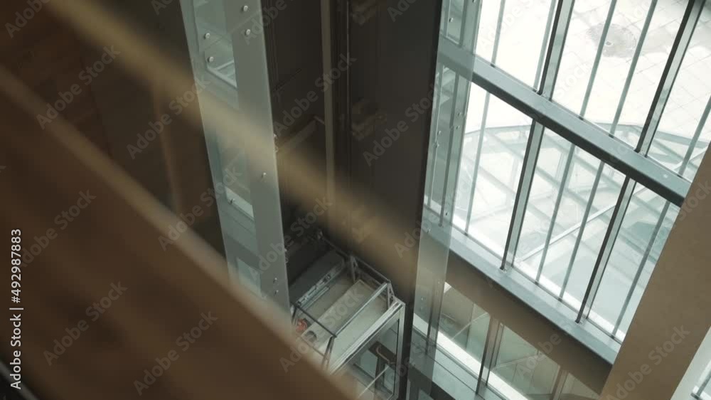 Empty open glass transparent elevator car rises up inside the building ...