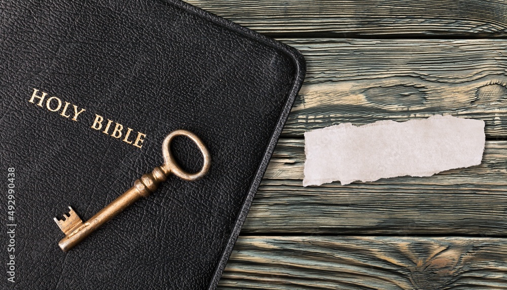 God Bible with an old, vintage key on a wooden table. Christian ...