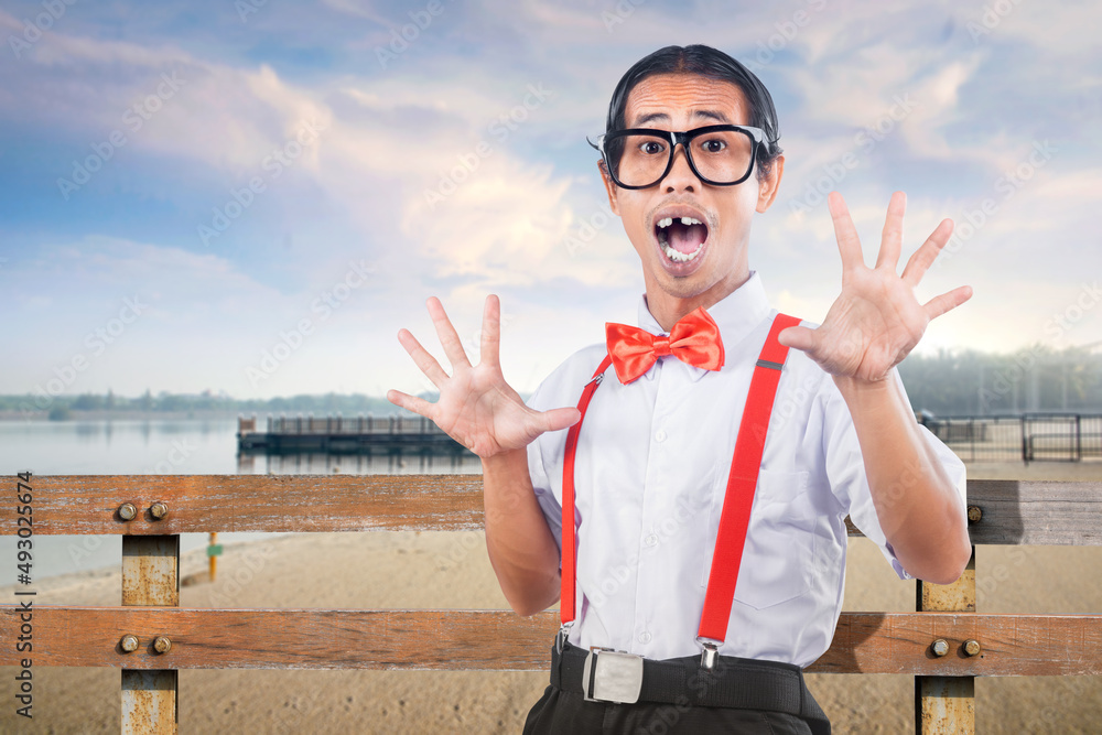 Foto de Asian nerd with ugly face with shocked expression do Stock | Adobe Stock