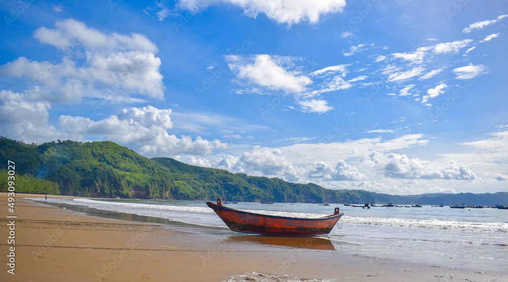 Traditional wooden fishing boats and beautiful hilly beach in East Java ...