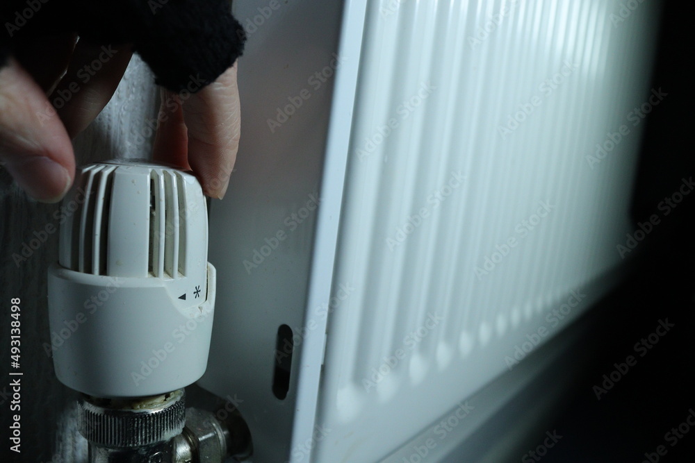 Rising Heating Costs - A gloved hand reaches for the dial on a radiator ...