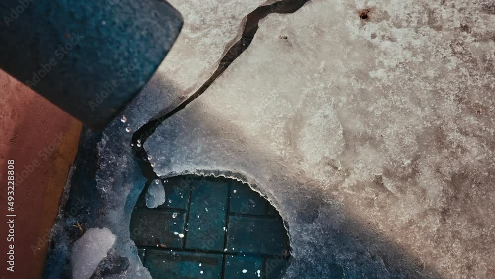 Melt water splashes and drips from a drain pipe into a puddle with the ...