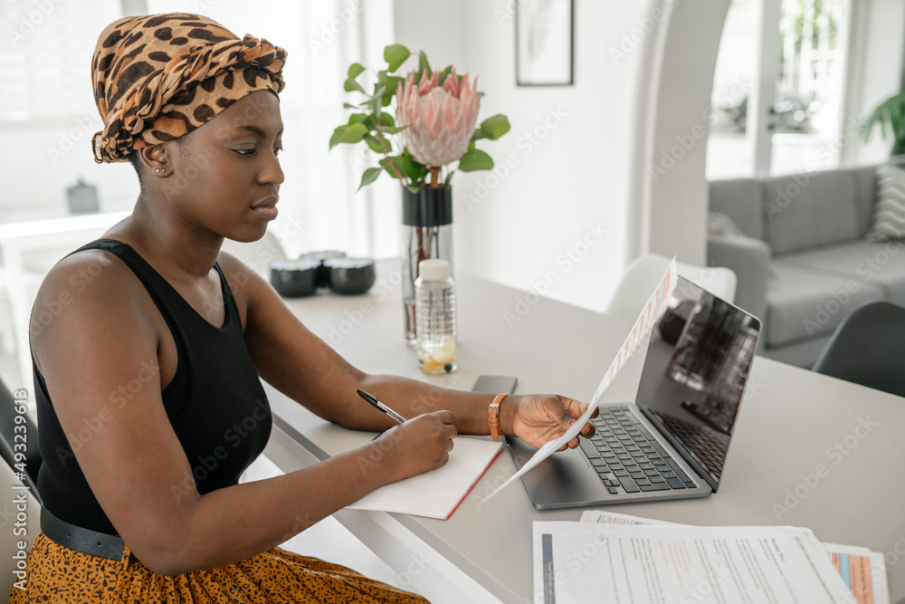 Black African woman studying online at home, traditional head tie scarf ...
