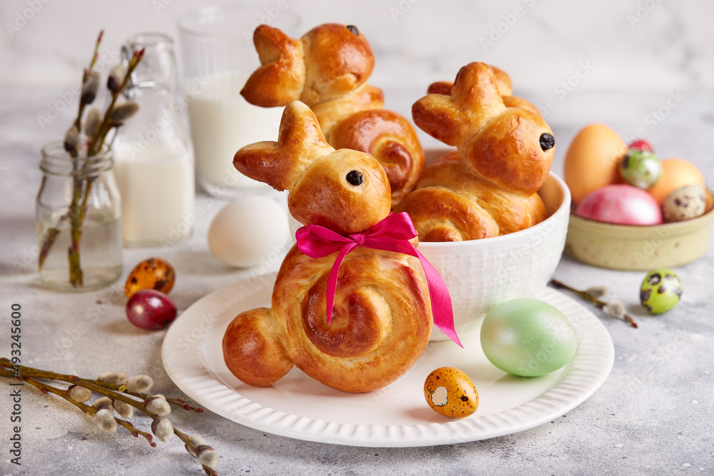 Buns made from yeast dough in a shape of Easter bunny, and colored eggs ...