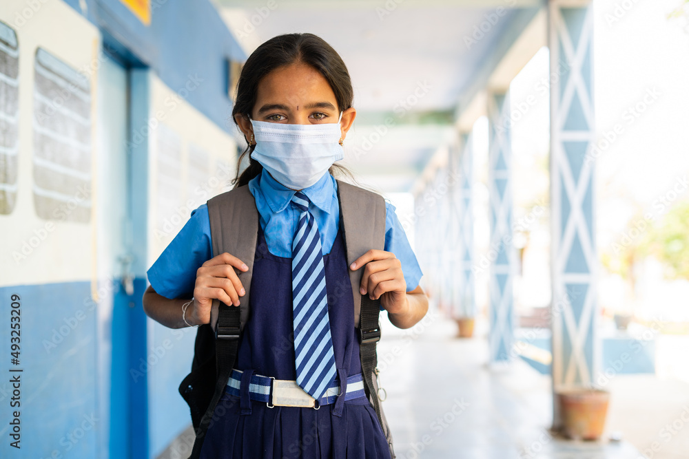 Girl kid in uniform with medical face mask standing at school corridor ...