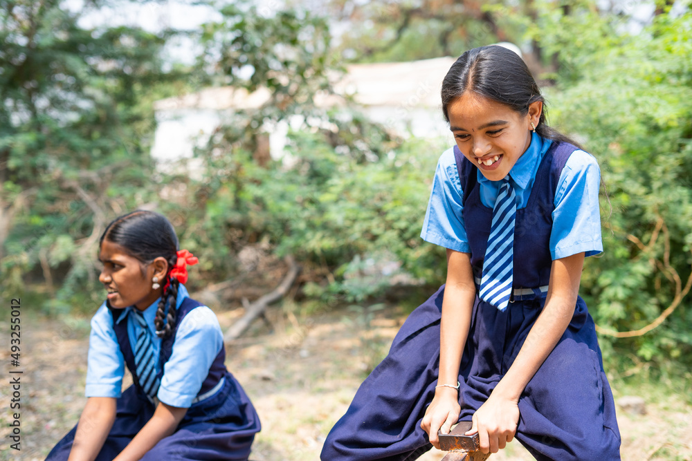 girl kids in uniform playing on seesaw game at school playground ...