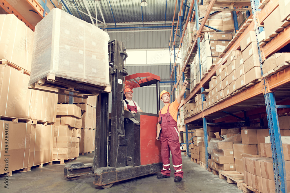 Warehousing and storage. warehouse workers works with forklift loader ...