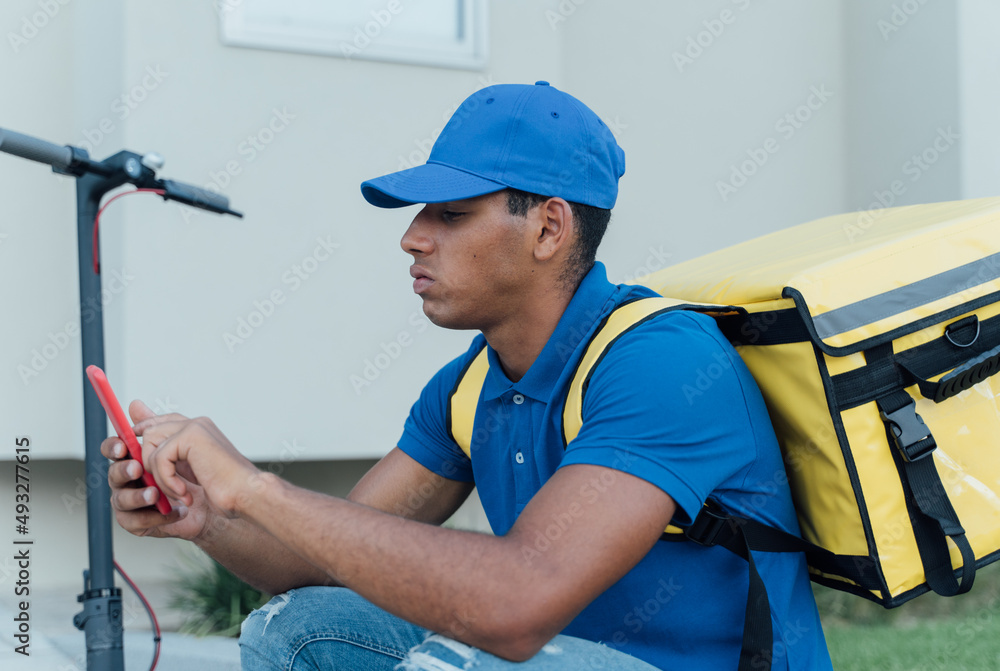 Young delivery driver waiting for a new order on the street. Checking ...