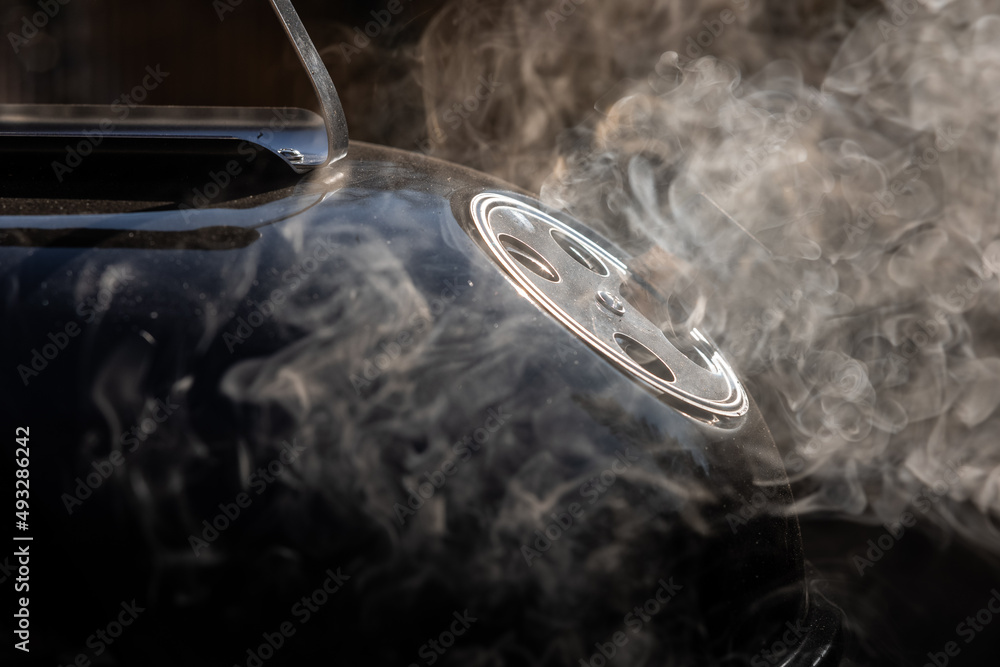 Smoke coming out from ventilation opening of a smoker grill. Round ...