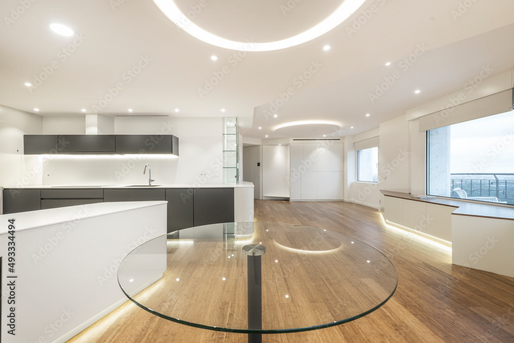 Circular glass dining table in loft with large windows, cabinets ...