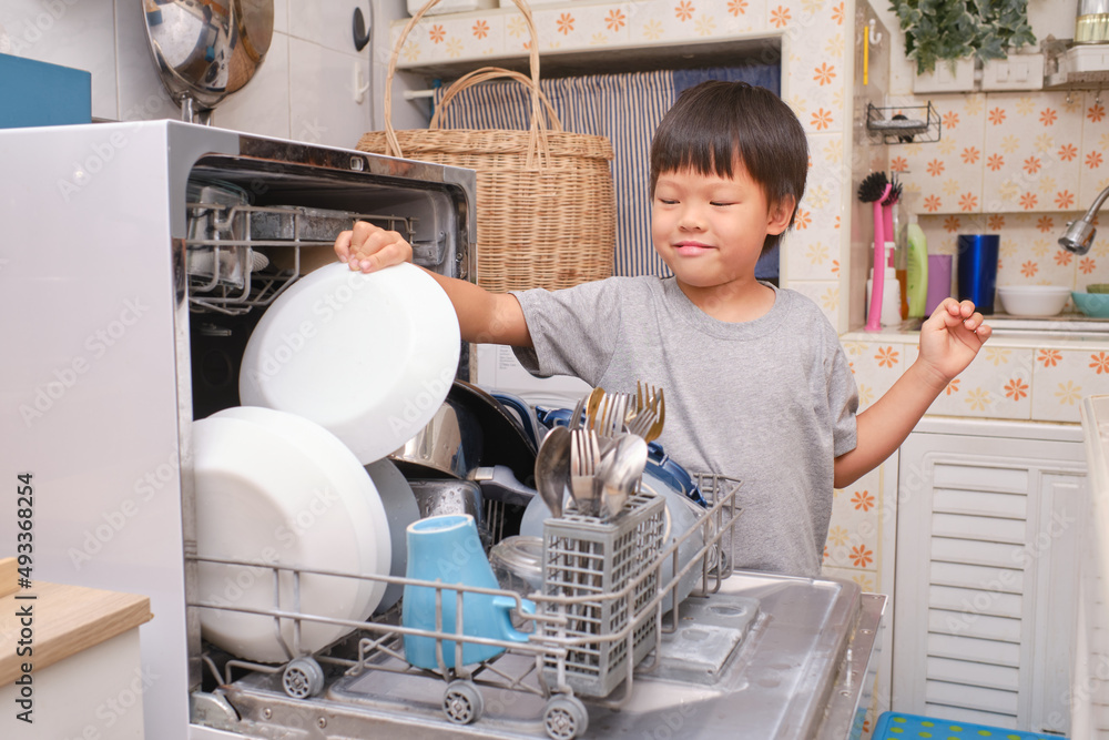 Cute Asian boy child having fun doing the dishes, washing dishes ...