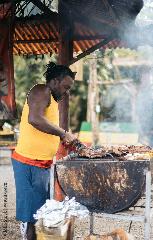 Afro-Caribbean man cooking on a barbeque Stock Photo | Adobe Stock