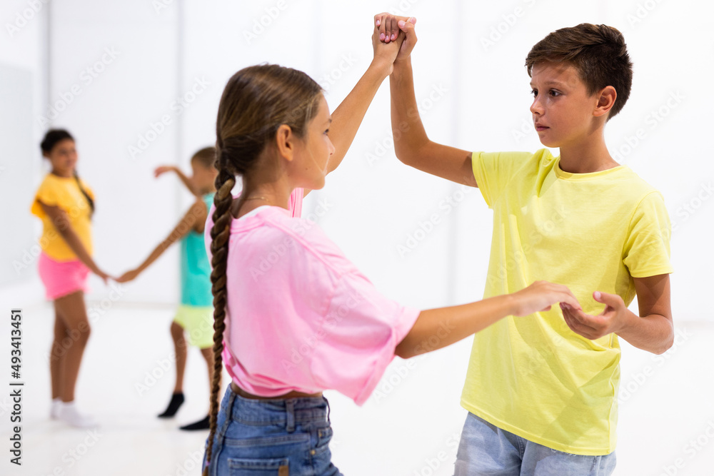Sporty preteen children learning to dance vigorous jive in pairs in ...