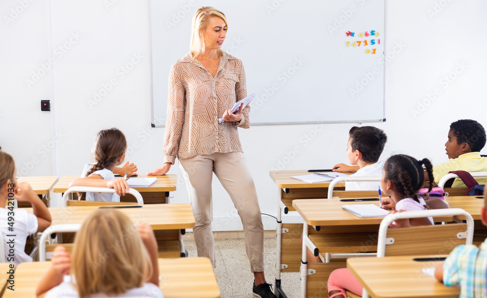 Adult female teacher is giving lecture for primary school students in ...