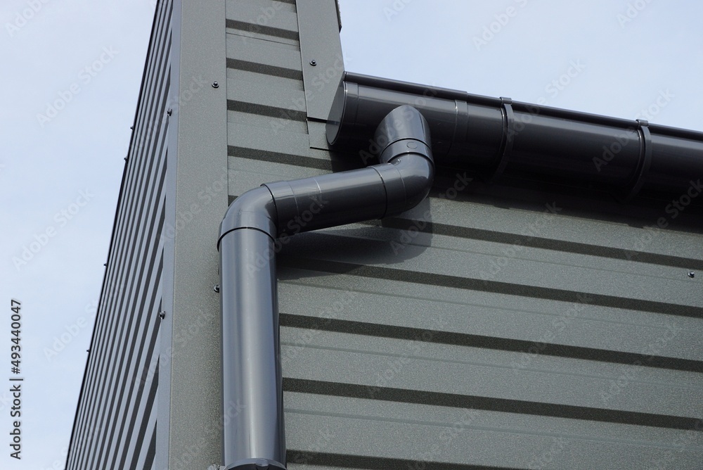long black plastic drain pipe on the iron wall of the building on the ...