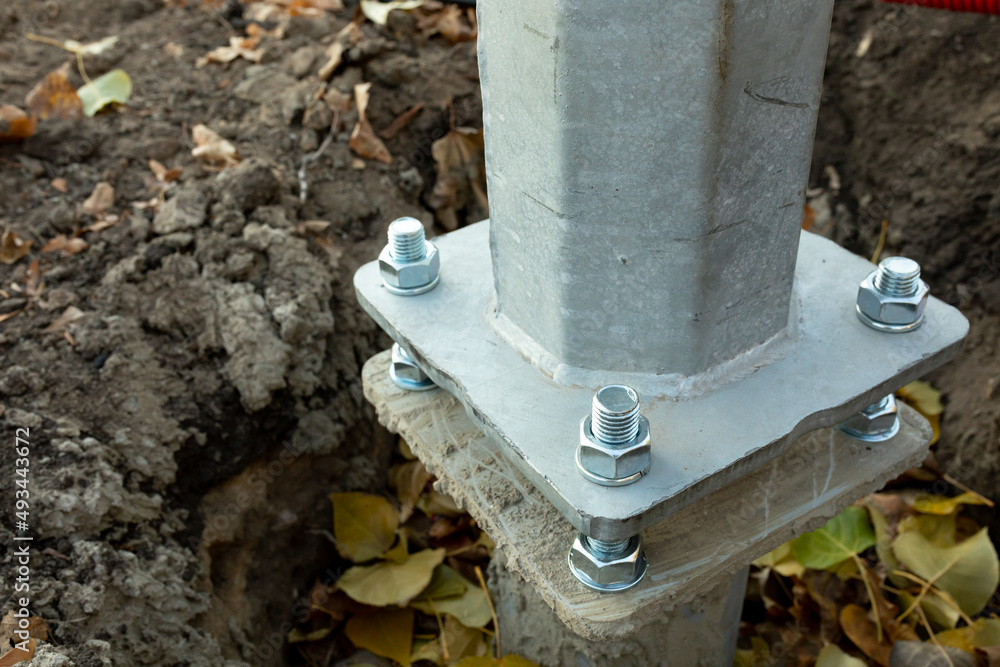 Metal pillar fastened to basement with anchor bolts and nuts. The ...