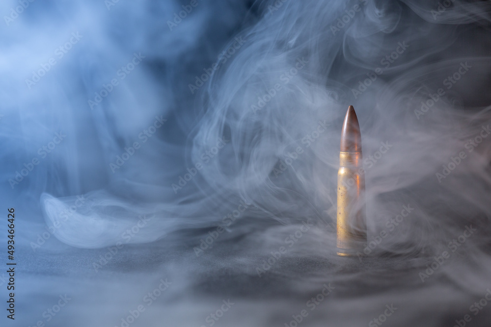 Assault rifle bullet in smoke. The cold light from the upper left ...