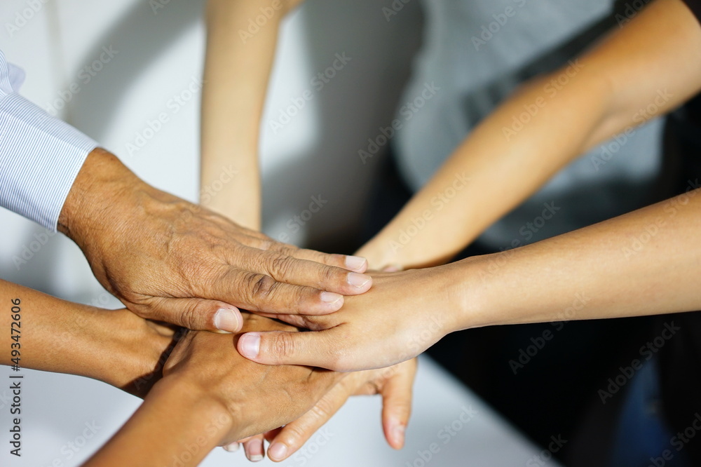 People of various ages holding hands (putting hands on top of each ...