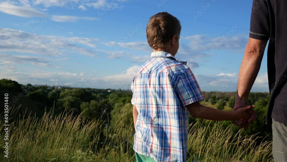 Father and son are standing on a hill at the edge of a cliff. Father ...