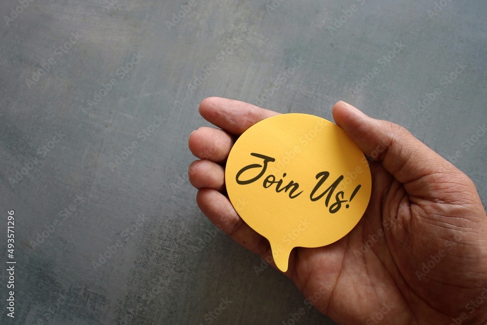 Hand holding yellow speech bubble with text JOIN US! with copy space ...