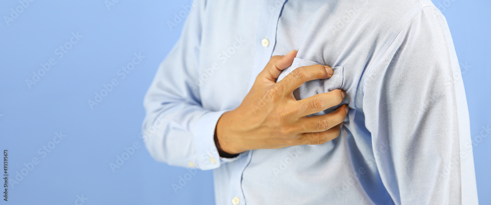 Hand squeezing the left chest pain on blue background concept of heart ...