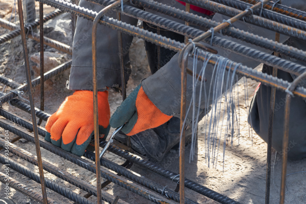 A worker uses steel tying wire to fasten steel rods to reinforcement ...