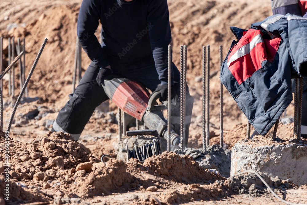 Foto de A worker with a jackhammer breaks concrete piles. Felling the ...