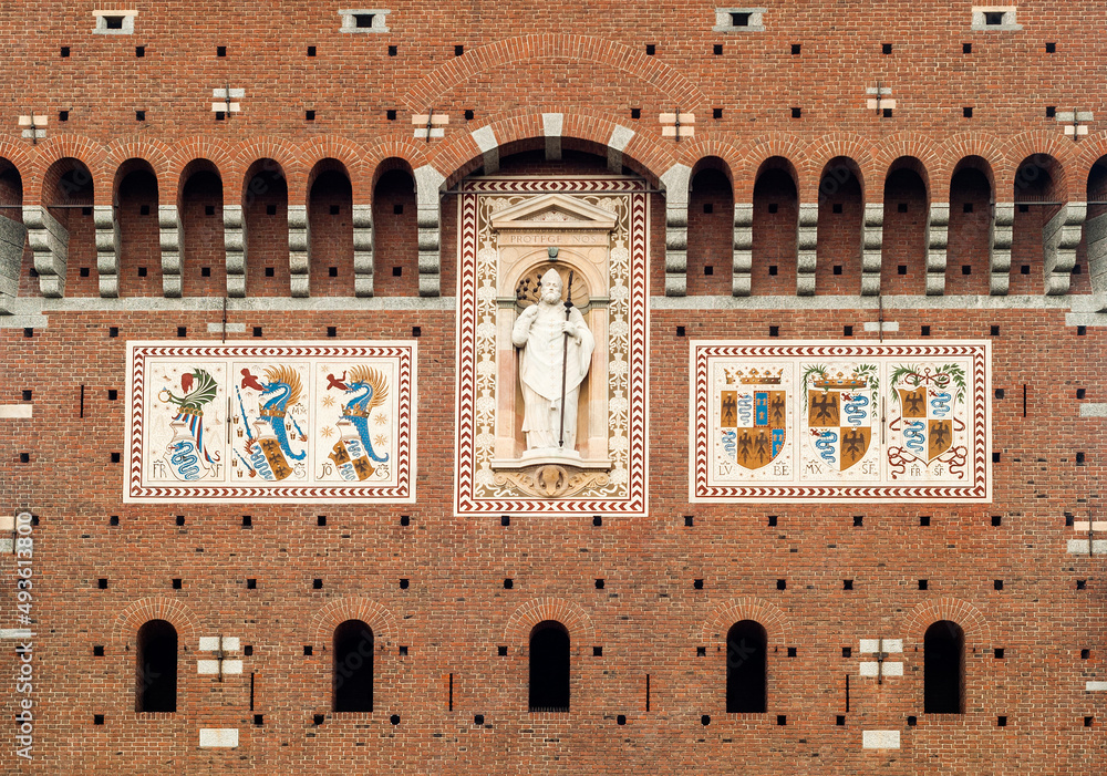 Fragment of facade of castle with statue of St. Ambrose and coats of ...