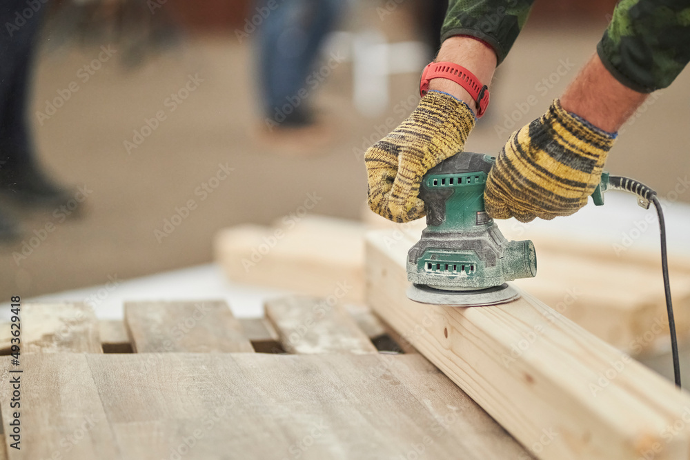 craftsman polishes a solid wood board with a sander, furniture ...