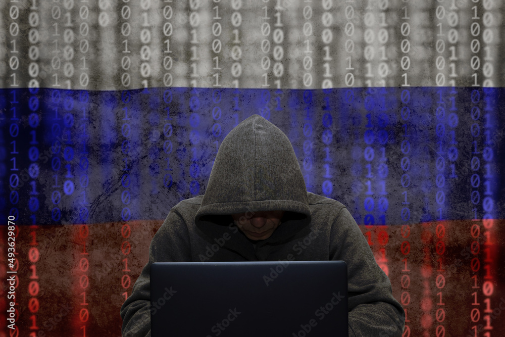 The troll factory. A hacker is sitting at a laptop and against the ...